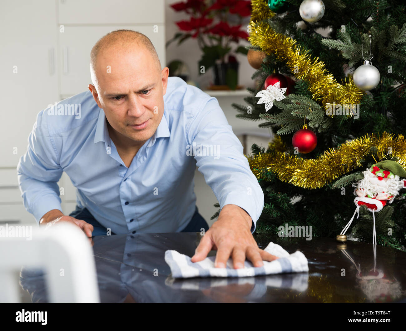 Positive man wipes the table before Christmas Stock Photo - Alamy