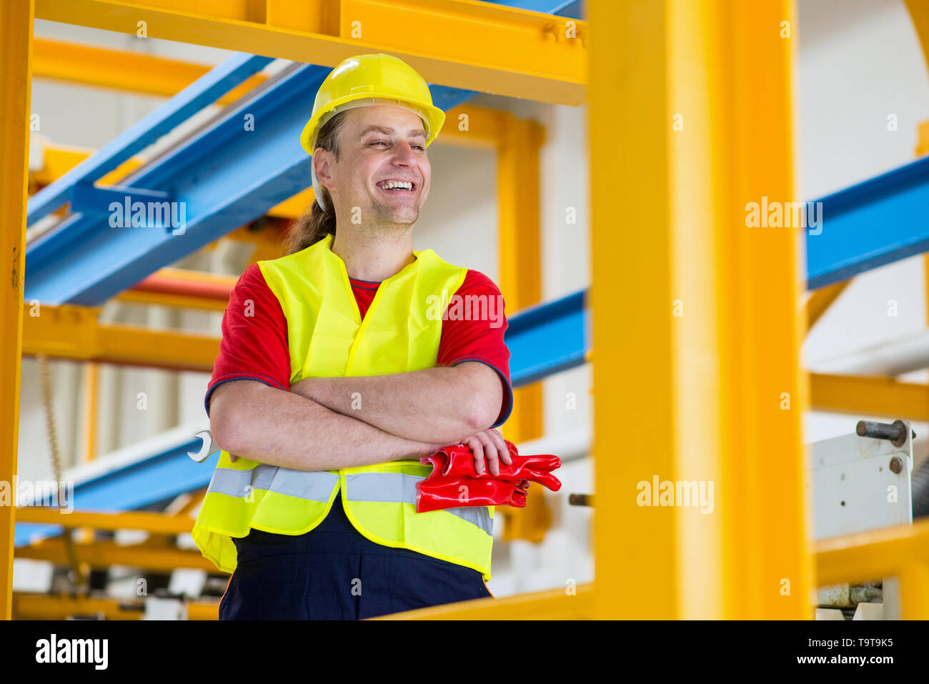Cheerful factory worker smiling with arms crossed Stock Photo - Alamy