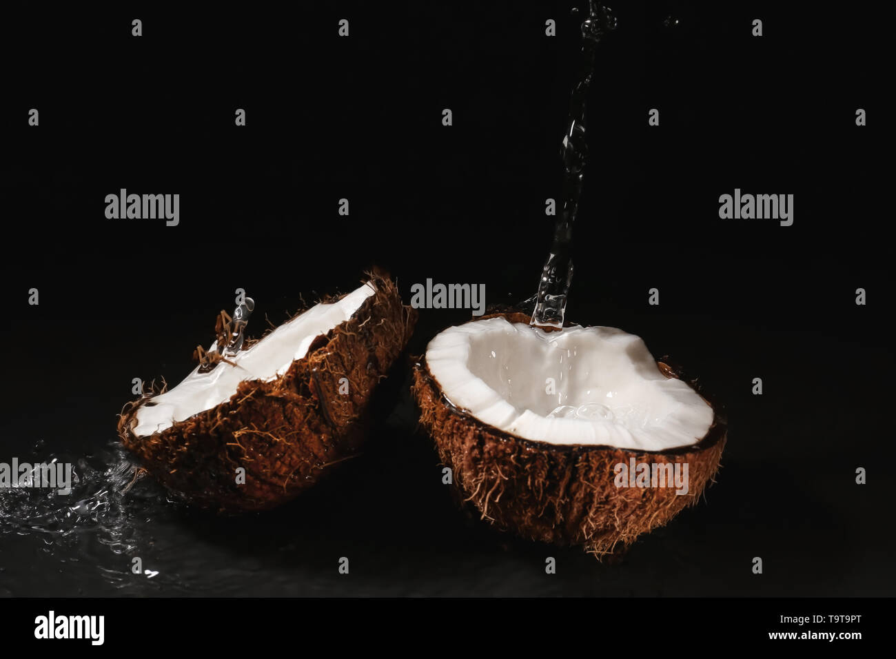Ripe coconut and splash of water on dark background Stock Photo - Alamy