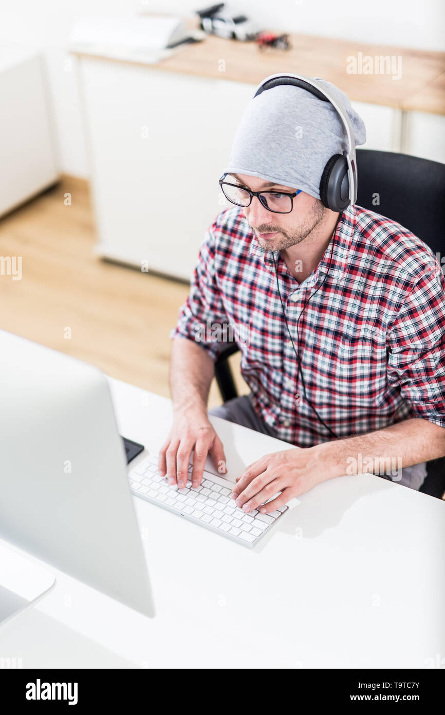 Modern programmer with headphones working on his computer Stock Photo ...