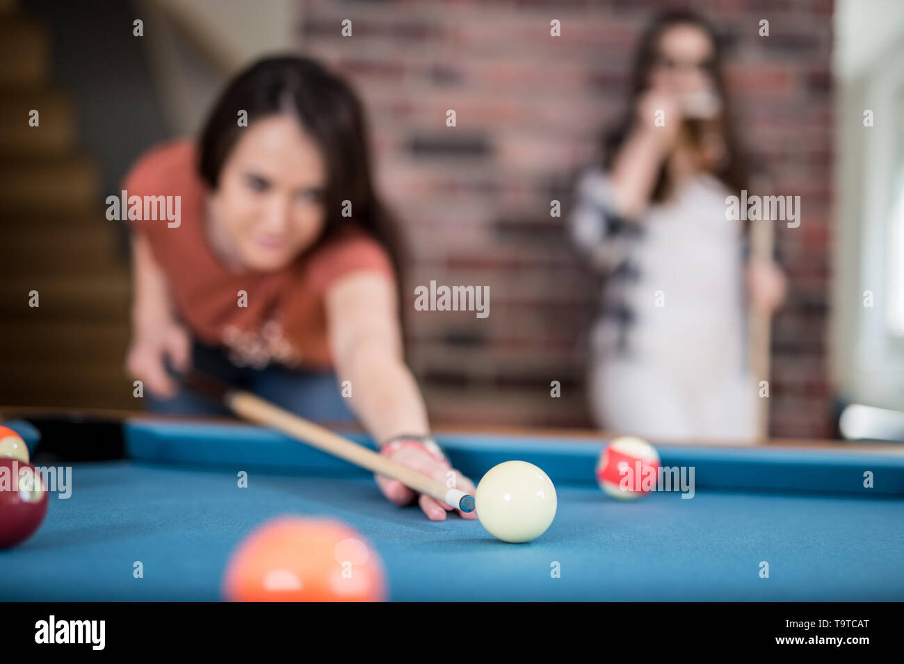 Two female students playing billiard game and drinking beer. Shallow ...