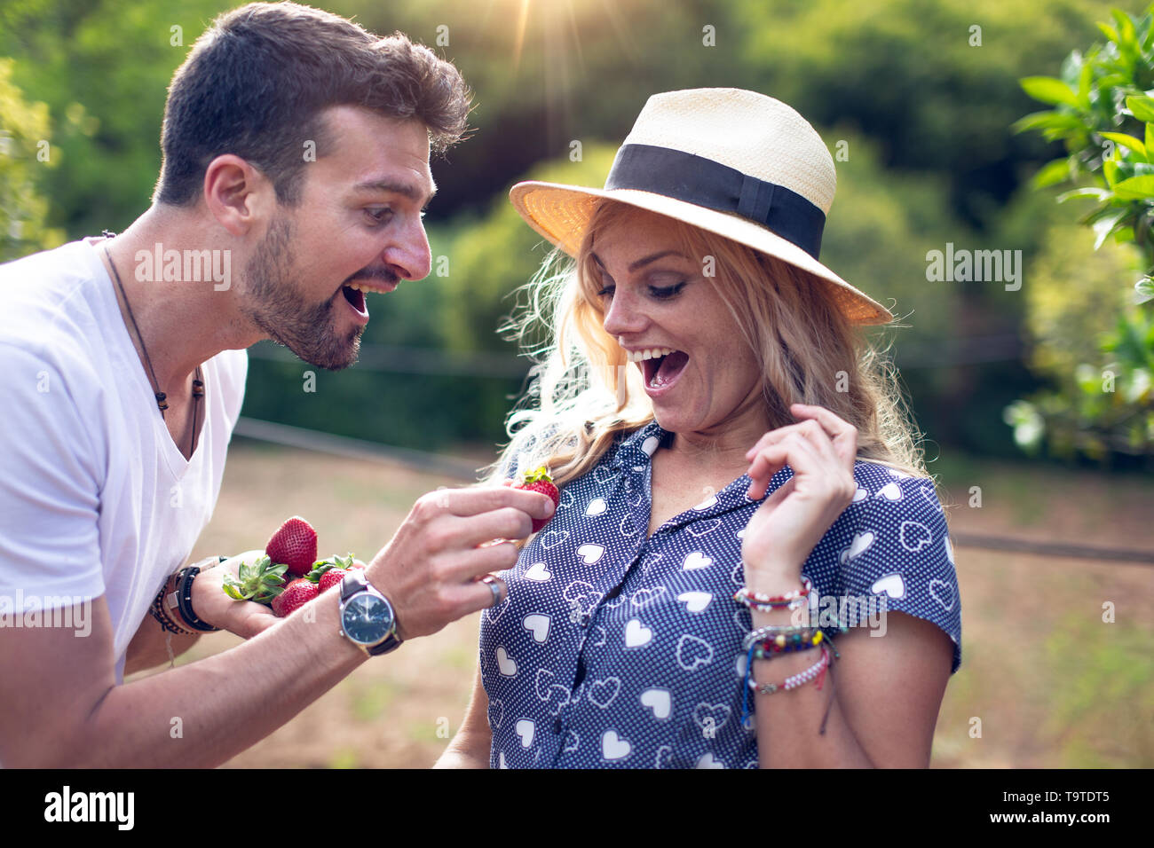 Spontaneous man giving strawberry to his surprised girlfriend, love and ...