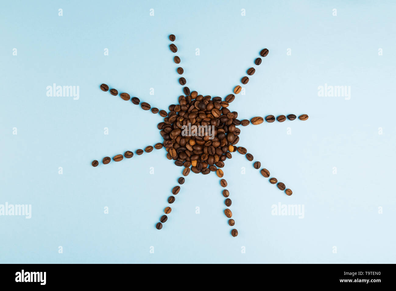 Sun made of coffee beans on blue background. Concept begins morning ...