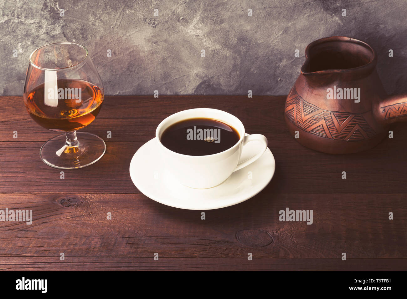 Coffee in white cup with cognac and clay cezve on wooden background ...