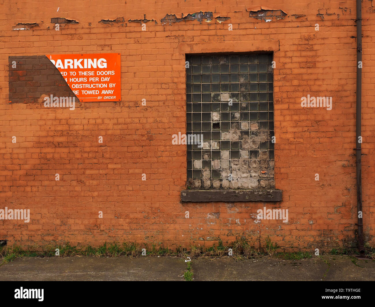 distressed red-brick building with flaking paint, broken "no parking ...