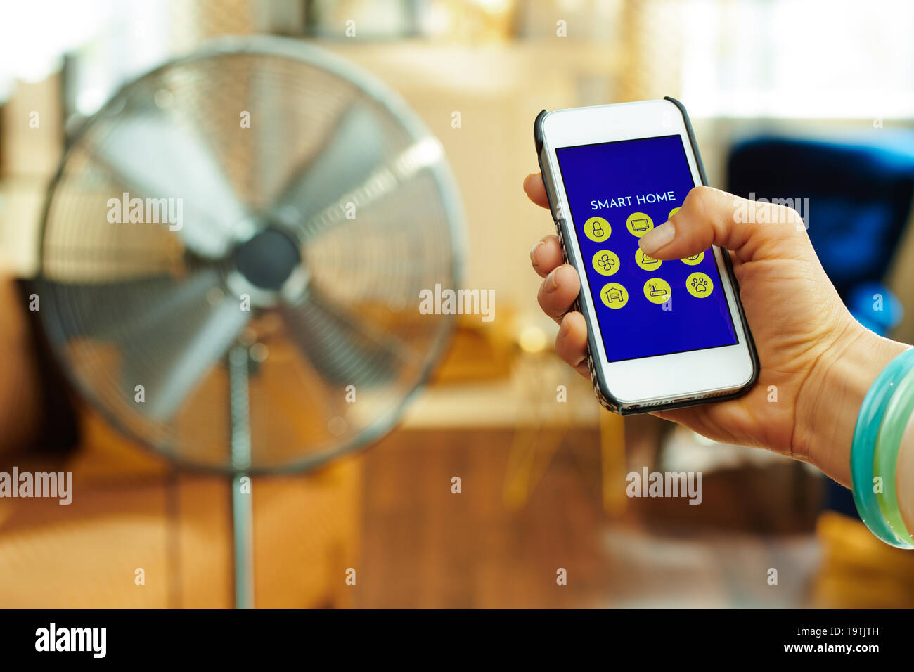 smartphone with smart home app in female hand controlling fan at modern ...