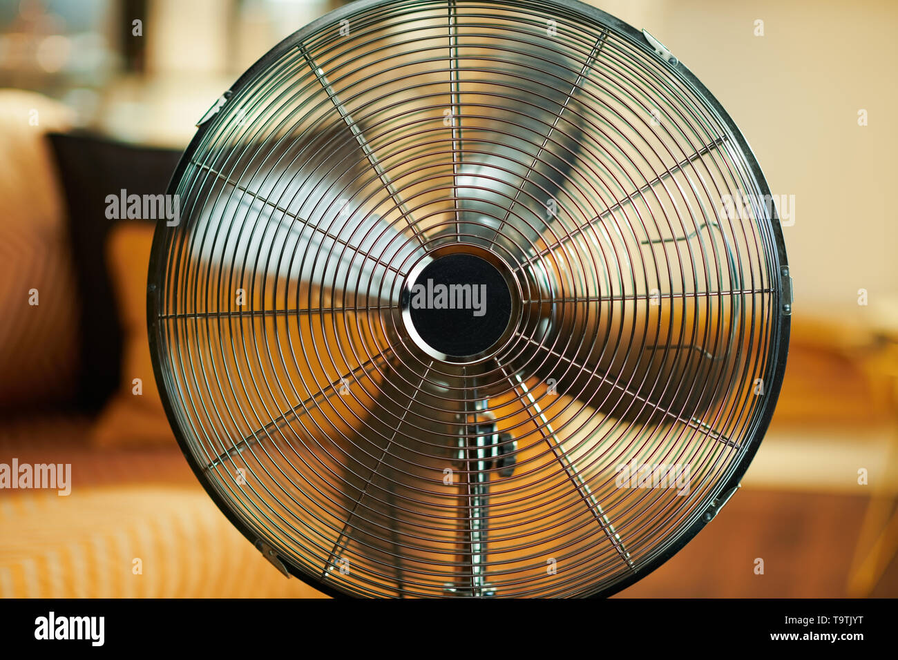 Closeup on working metallic floor standing fan at modern home in sunny ...