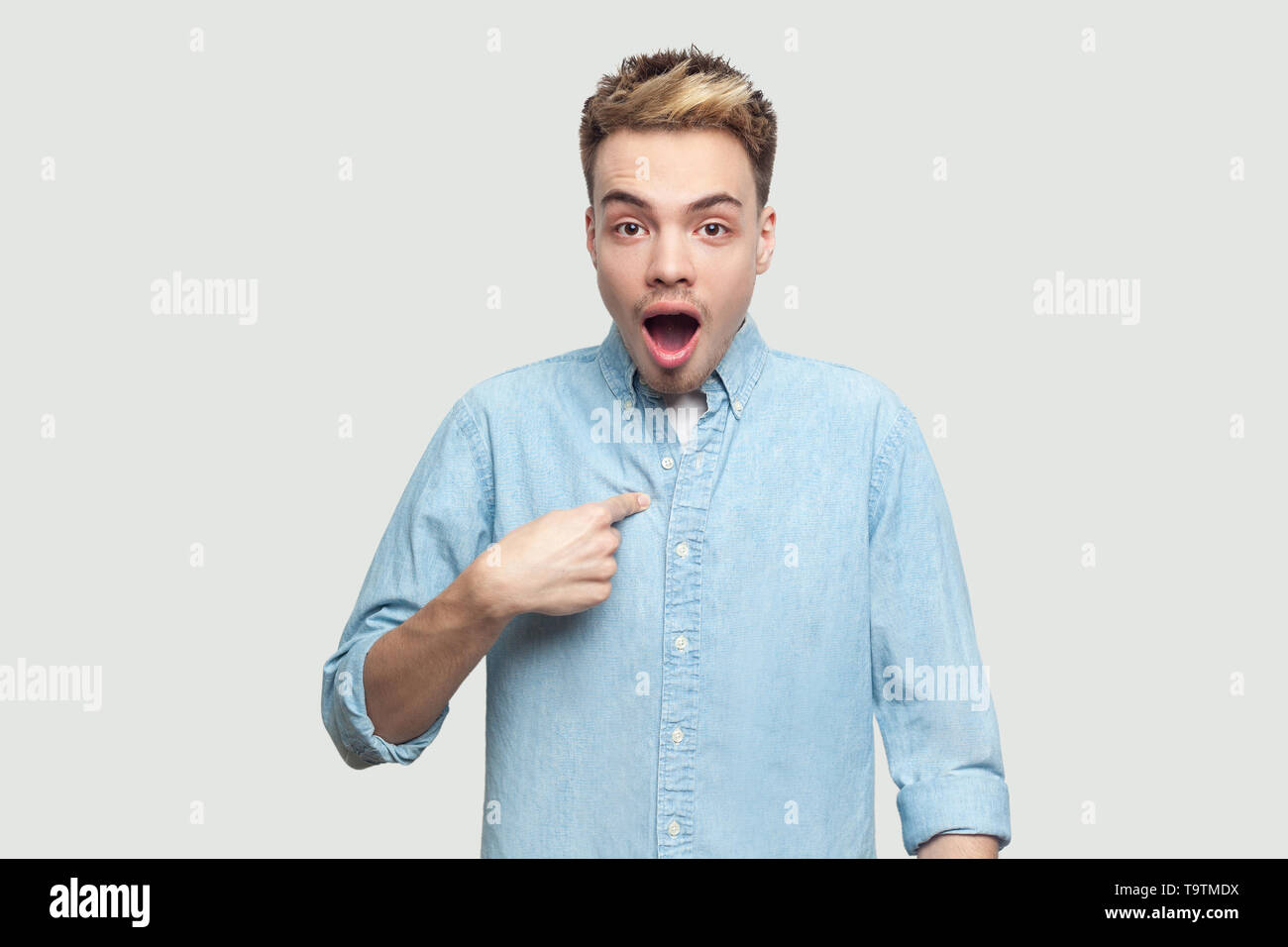Who? me? Portrait of shocked handsome young man in light blue shirt ...