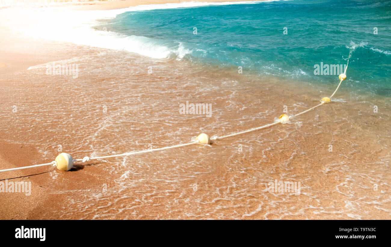 Closeup image of plastic floating buoys connected in line by rope lying ...