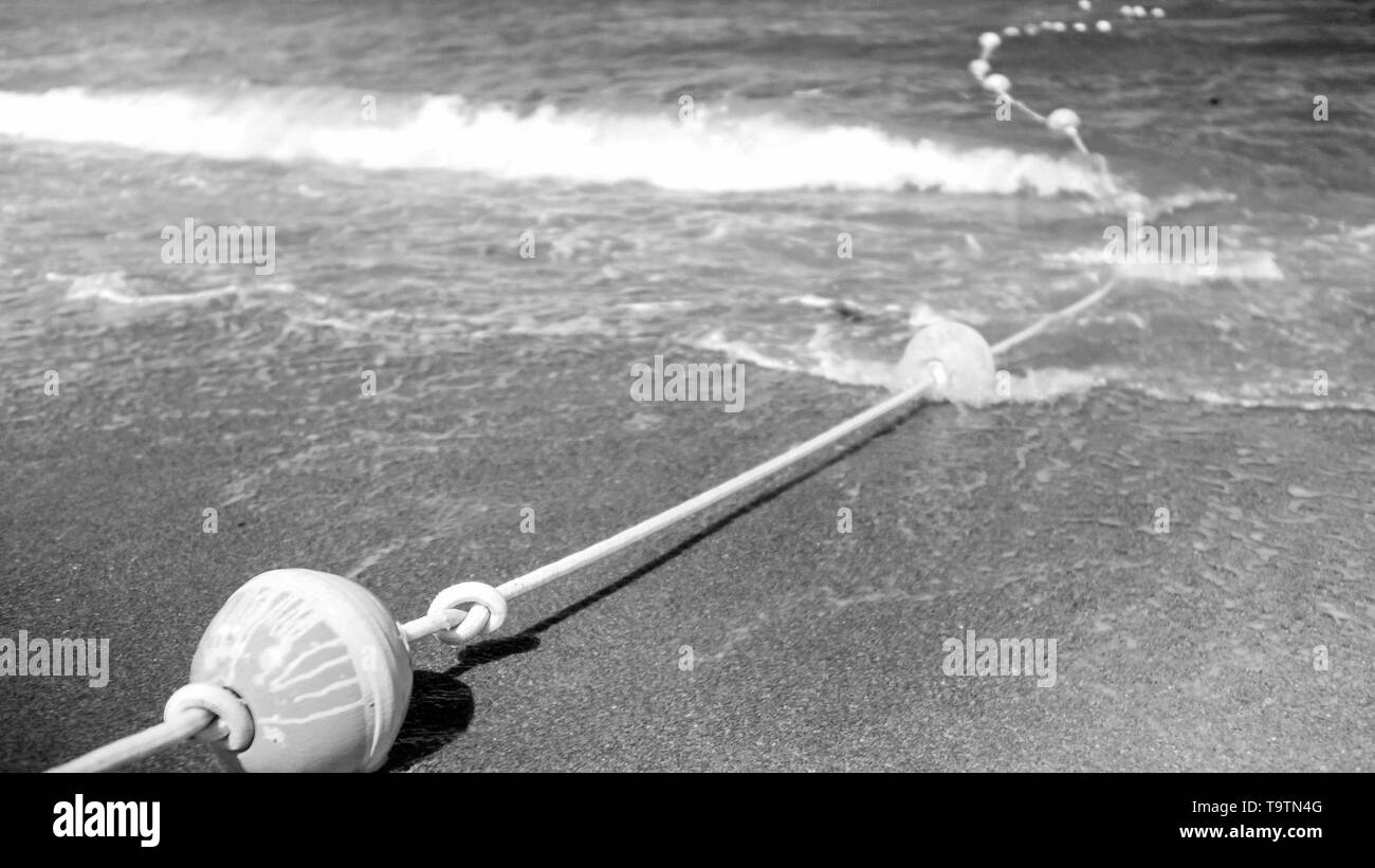 Black and white image of life saving buoy line on the rope lying on the ...