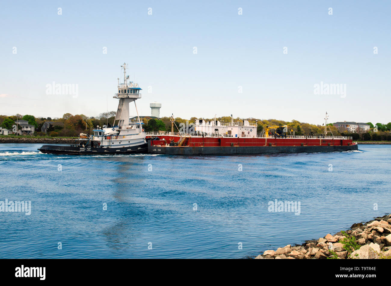 Tugboat pushing a fuel barge through the Cape Cod Canal with blue sky ...