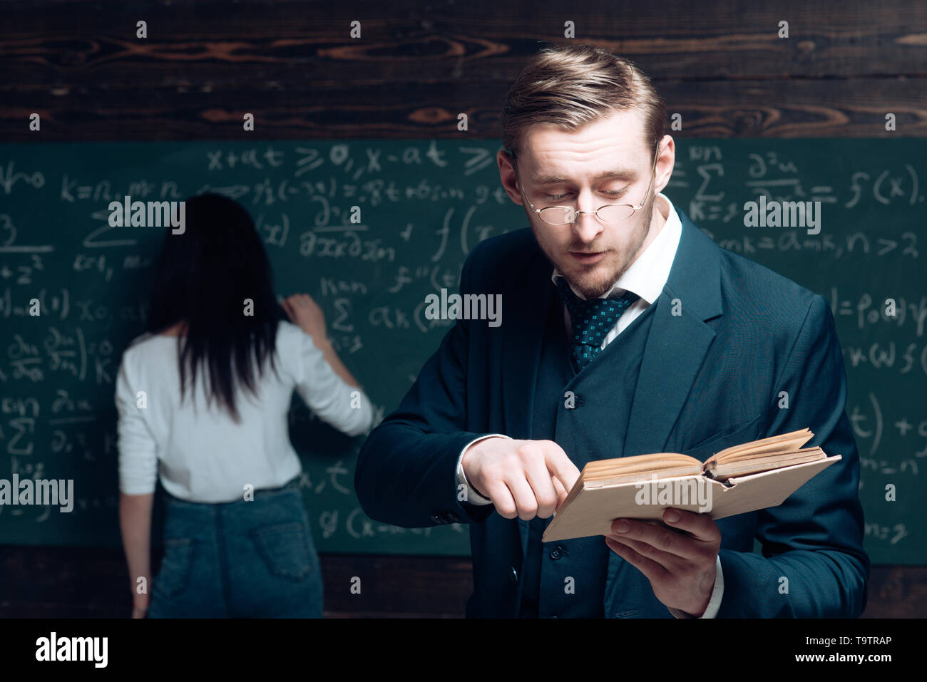 Concentrated professor reading article to the class while young female ...