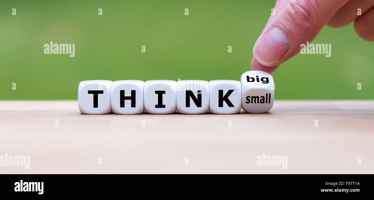 Hand turns a dice and changes the expression "think small" to "think ...