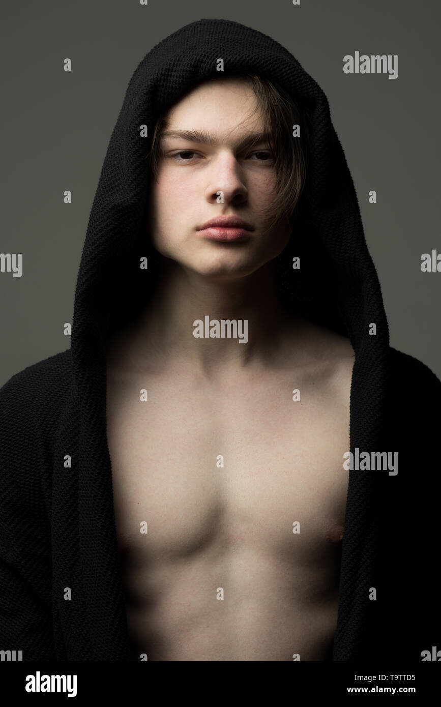 Teenage boy in black bathrobe isolated on gray background. Closeup ...