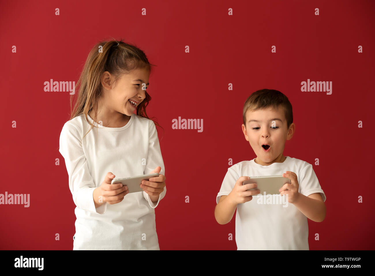 Cute little children playing with smartphones on color background Stock ...