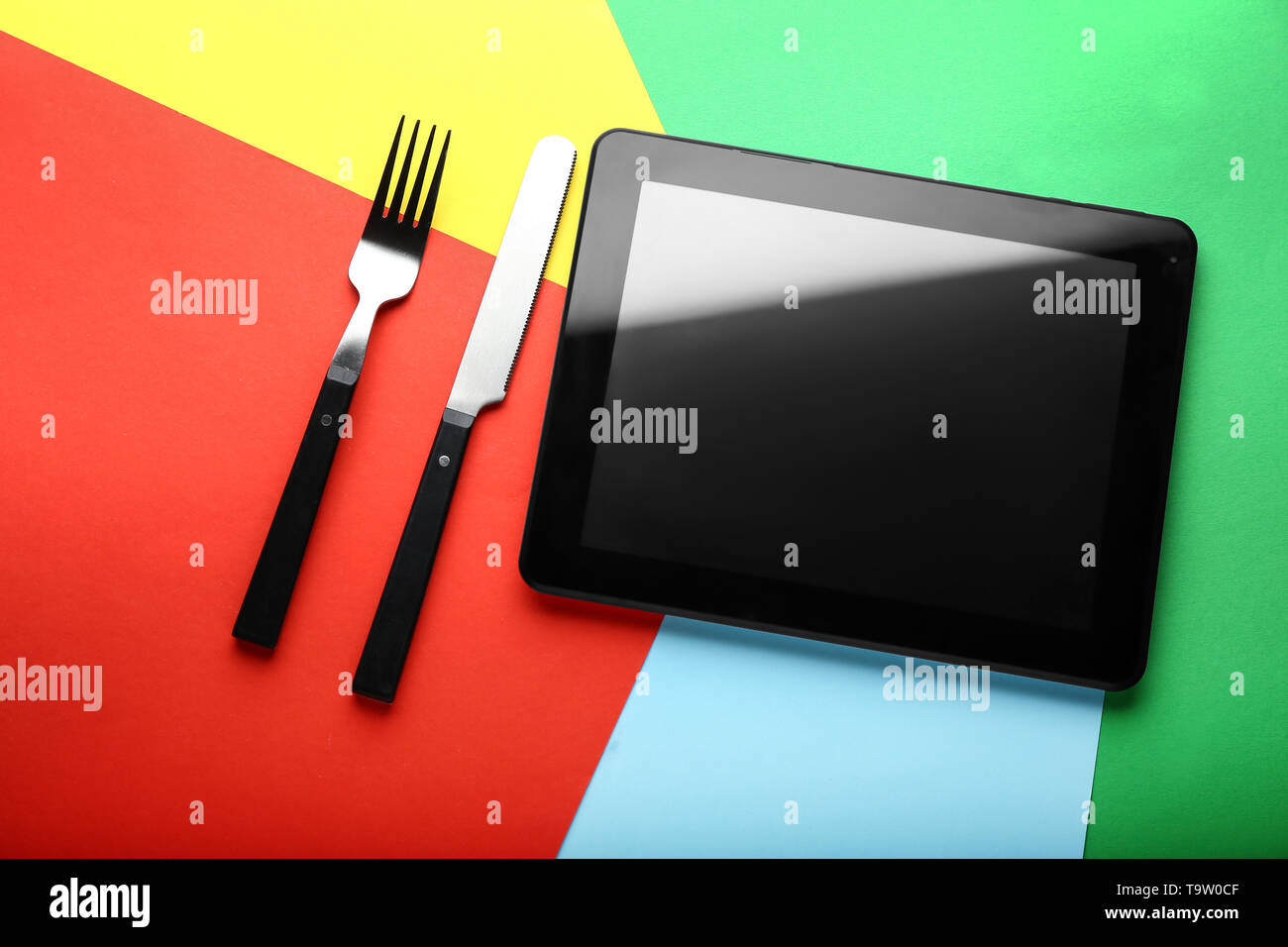 Tablet PC with cutlery on color background. Template for menu Stock ...