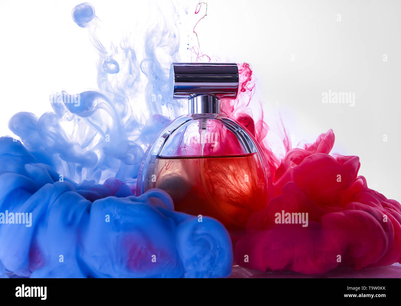 Bottle of perfume in color smoke on white background Stock Photo - Alamy
