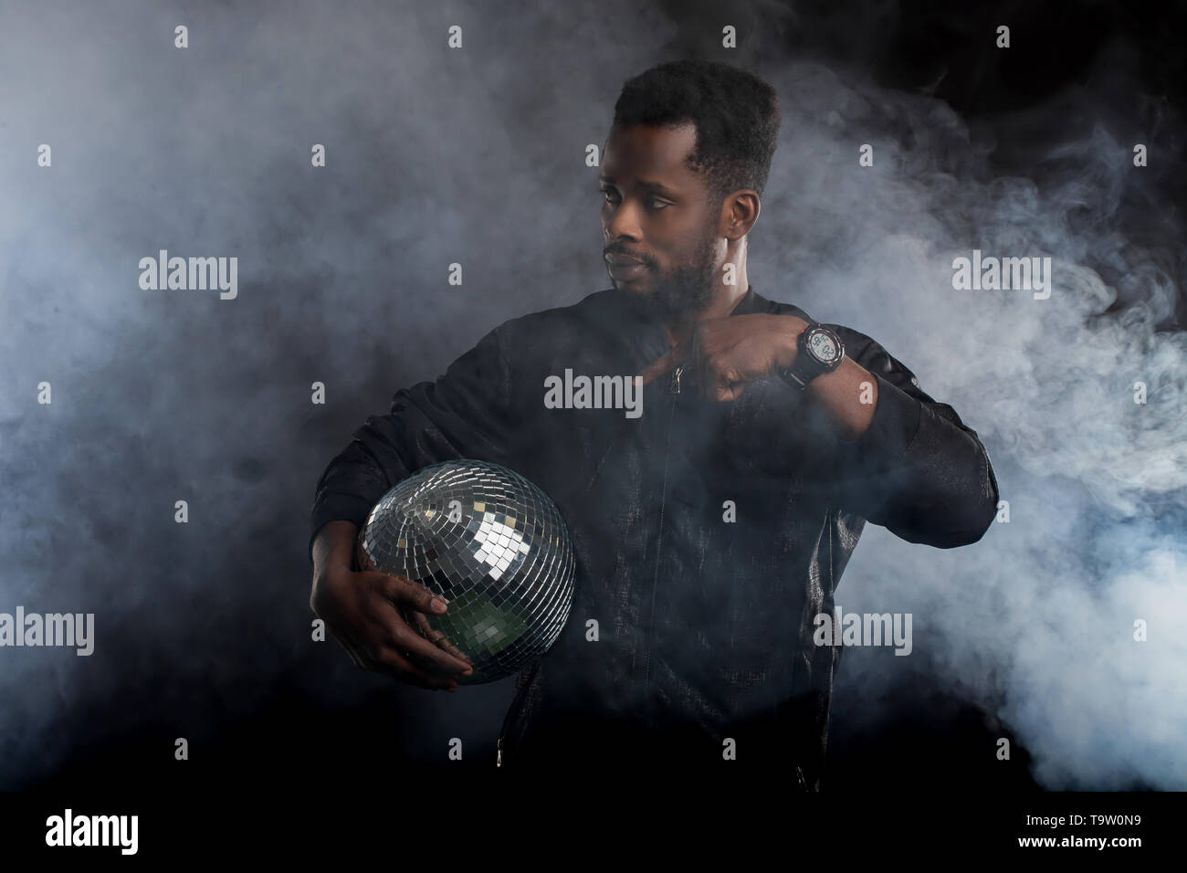 Confident brutal dark skinned man holding disco ball, looking at camera ...