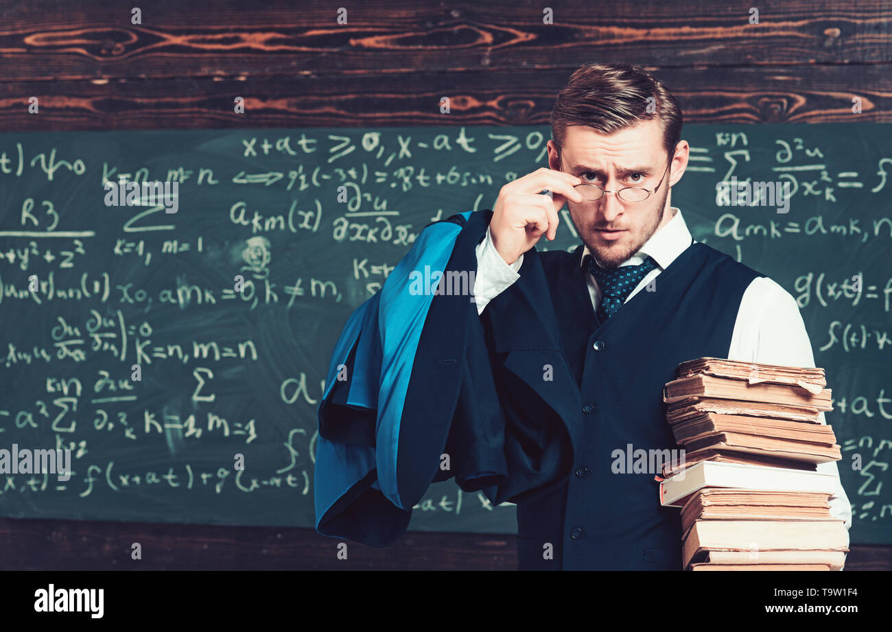 Young professor holding pile of books looking over his glasses ...