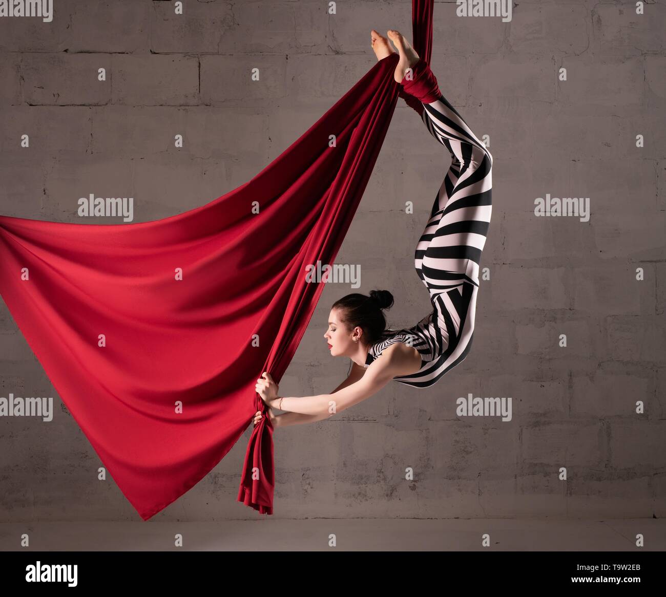 Young gymnast hanging on red cloth Stock Photo - Alamy