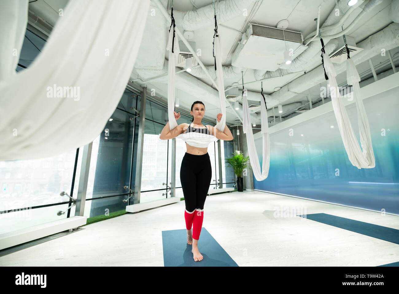 Woman standing on mat before practicing aerial yoga Stock Photo - Alamy