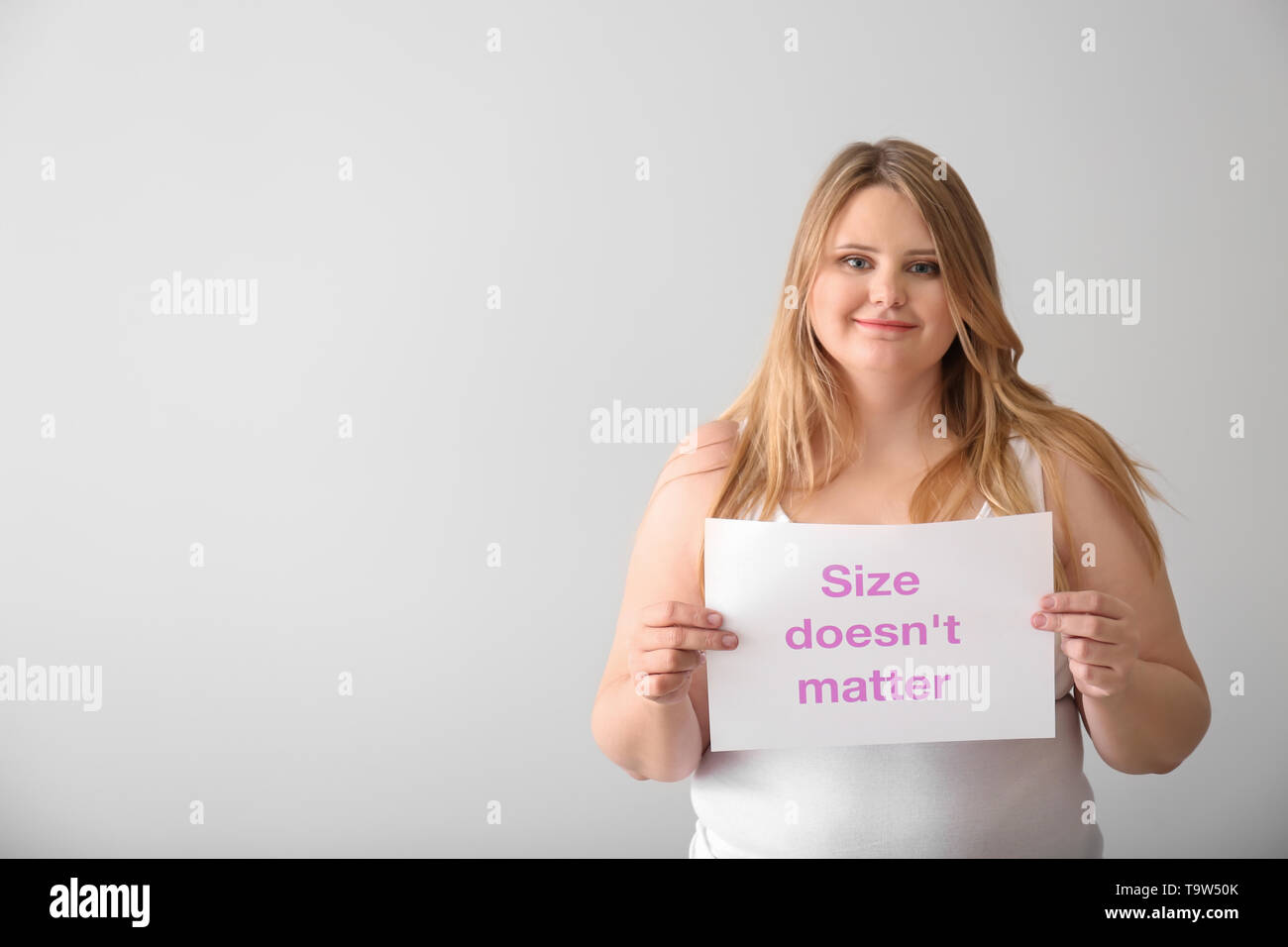 Beautiful plus size girl holding paper sheet with text SIZE DOESN'T ...