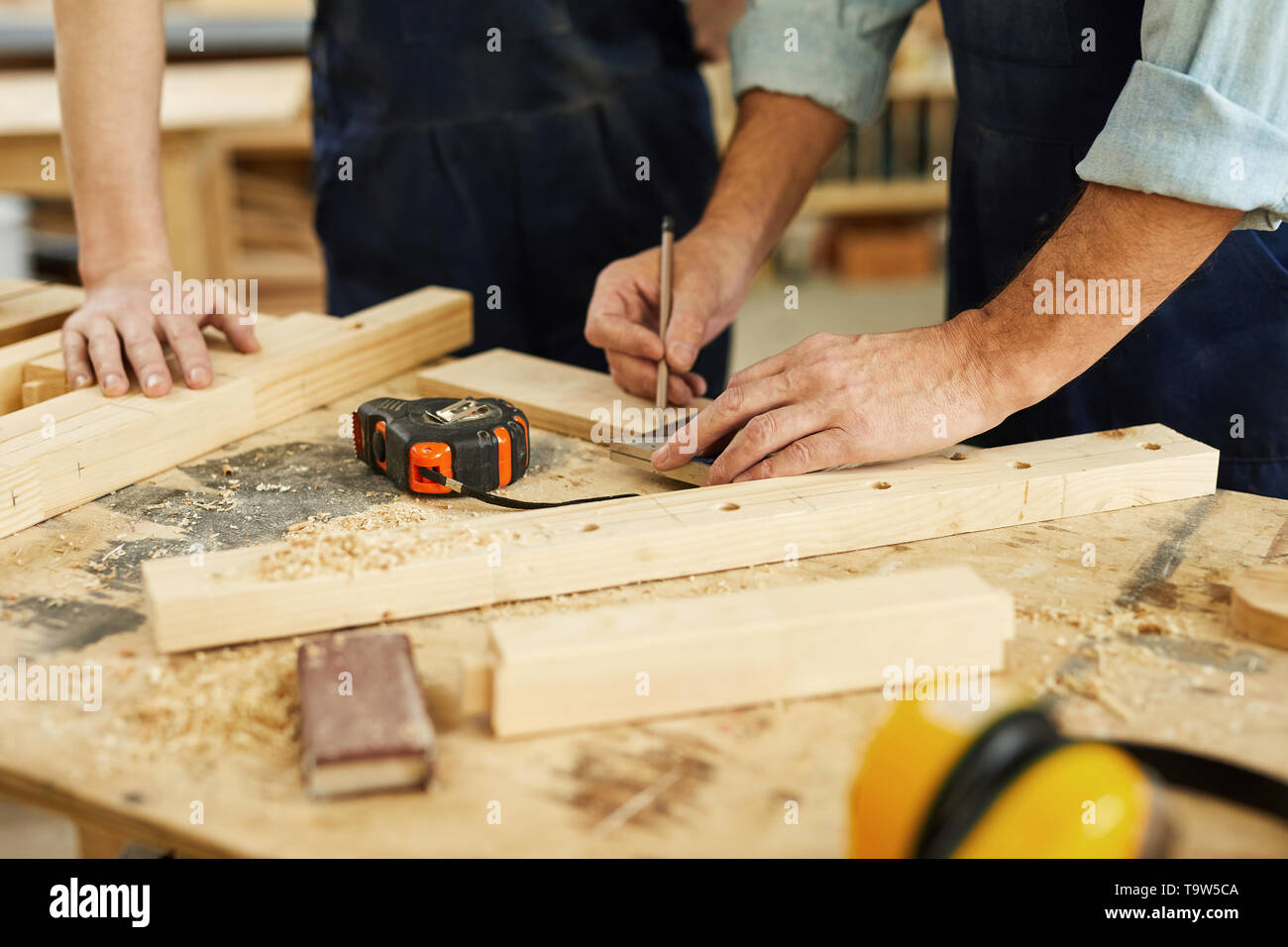 Close up of carpenters workstation with senior man measuring wood, copy ...