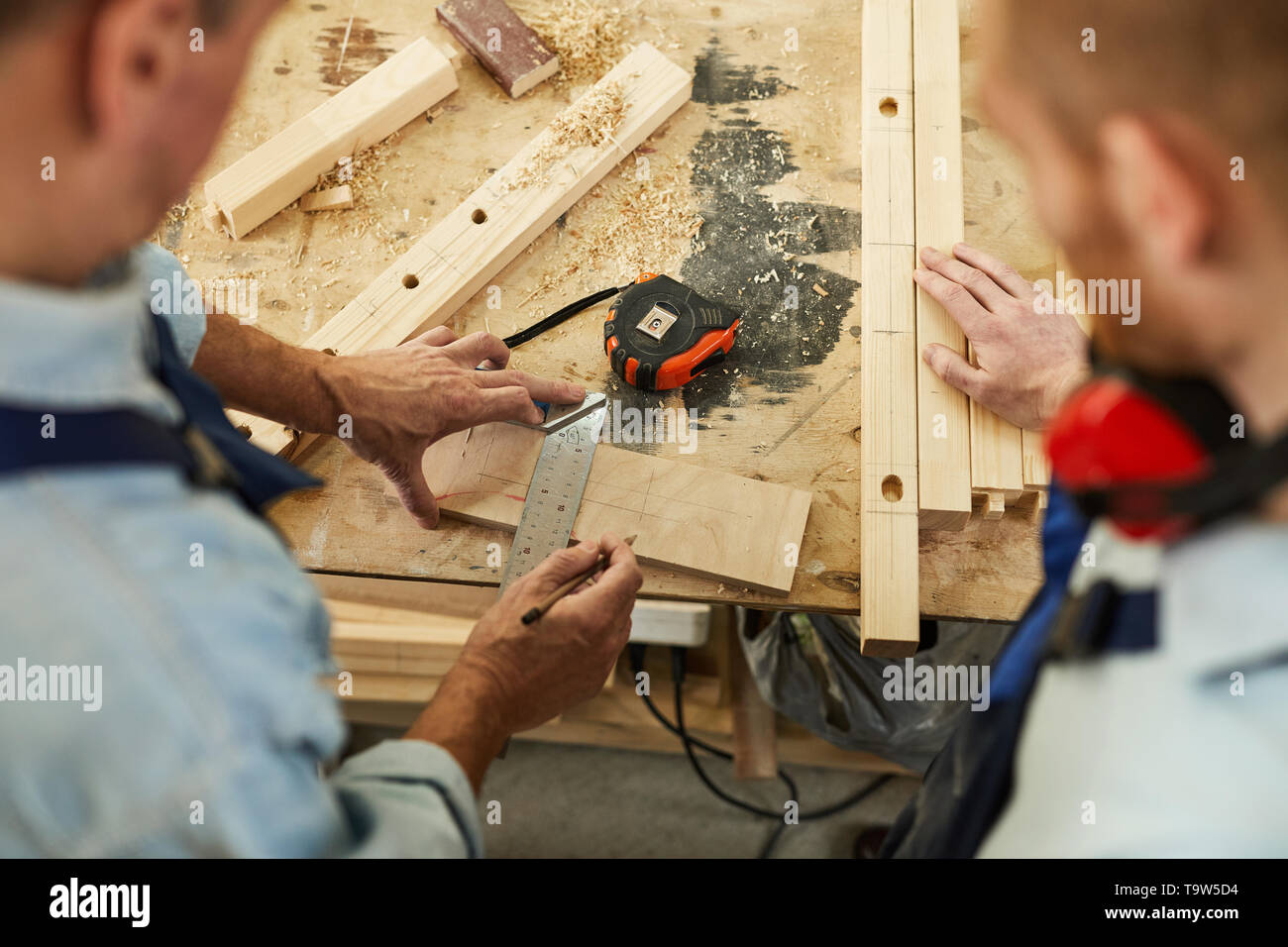 Top view closeup of carpenters workstation with senior man measuring ...