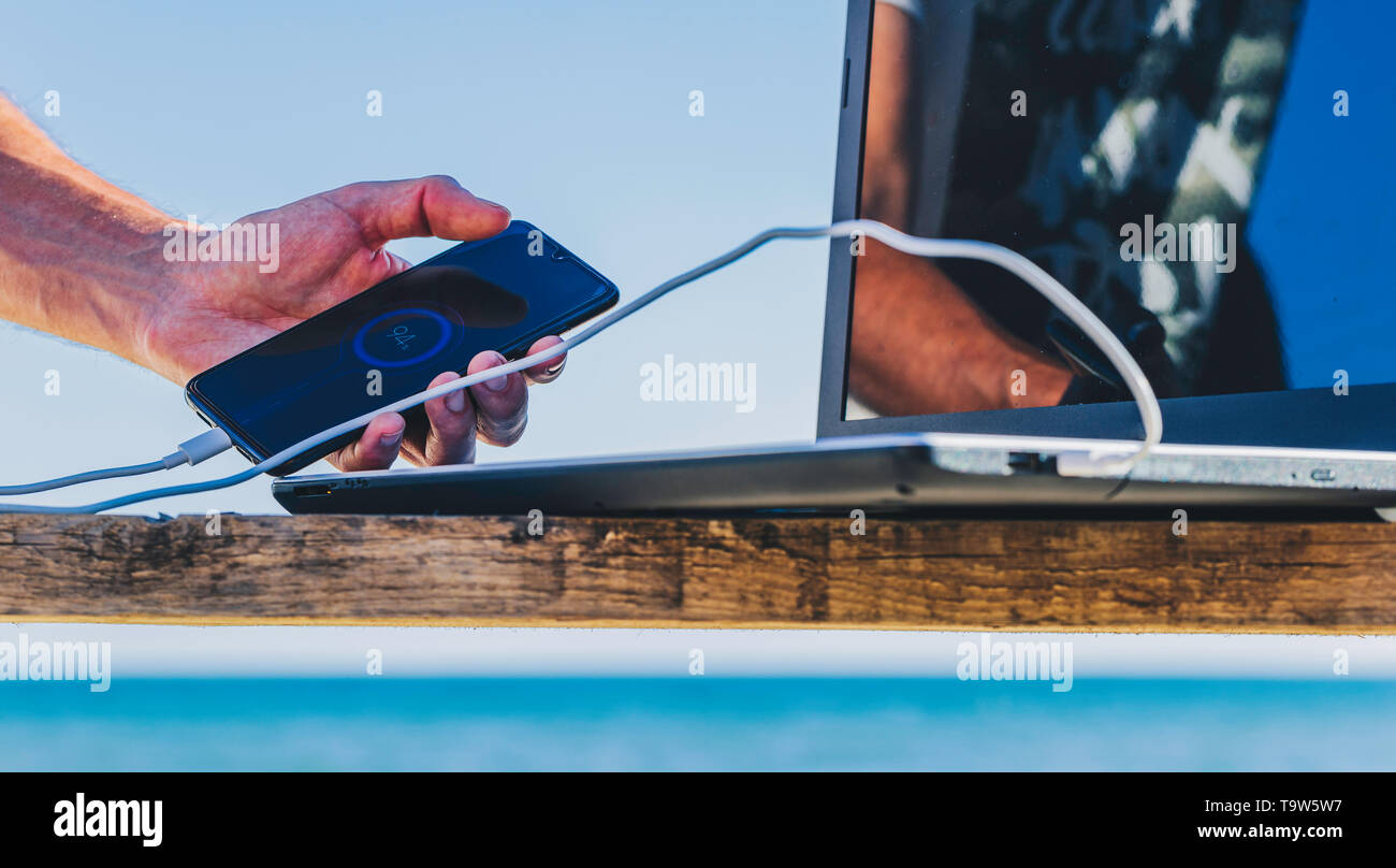 Plug in USB cord charger of the mobile phone with a laptop, portable ...