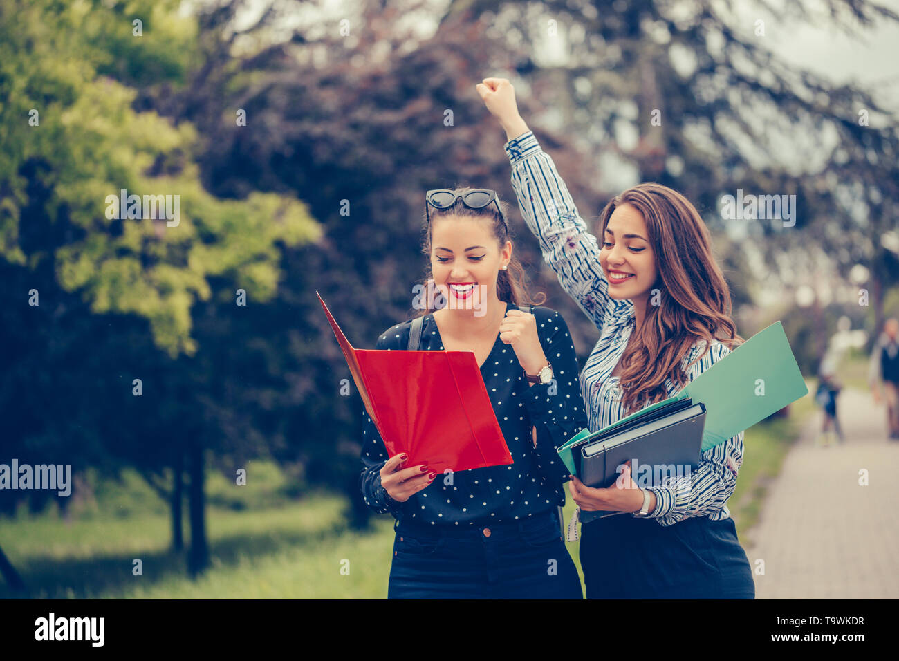 Two female friends, students celebrating success in a park - Image ...