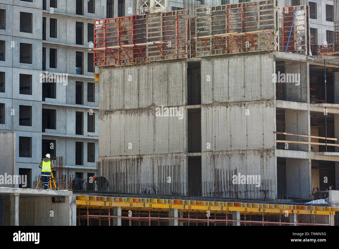 The builder in yellow overalls makes a topographic survey against the ...