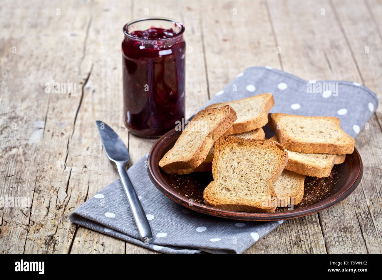 Toasted cereal bread slices on grey plate and jar with homemade cherry ...