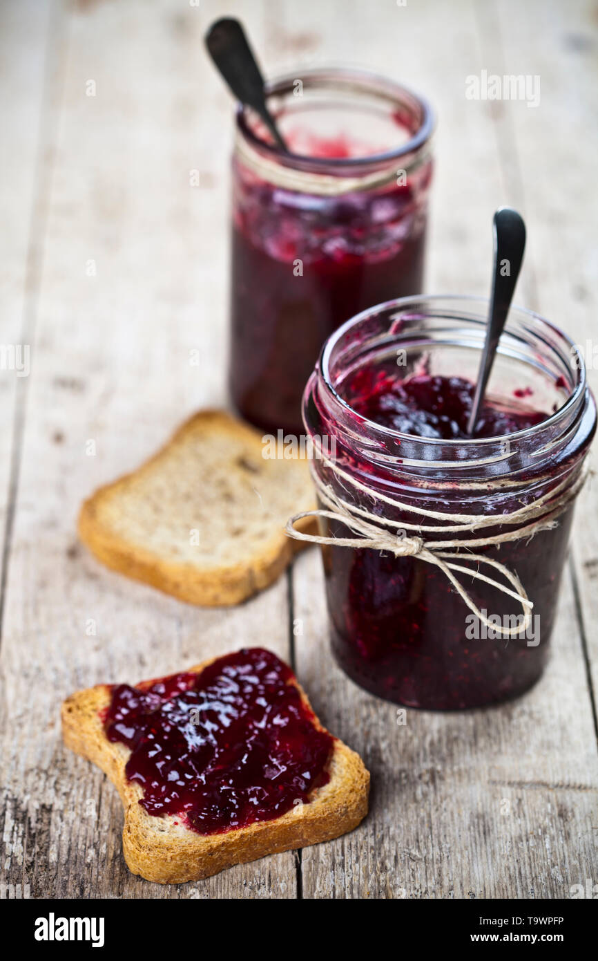 Toasted cereal bread slices and jars with homemade wild berries and ...