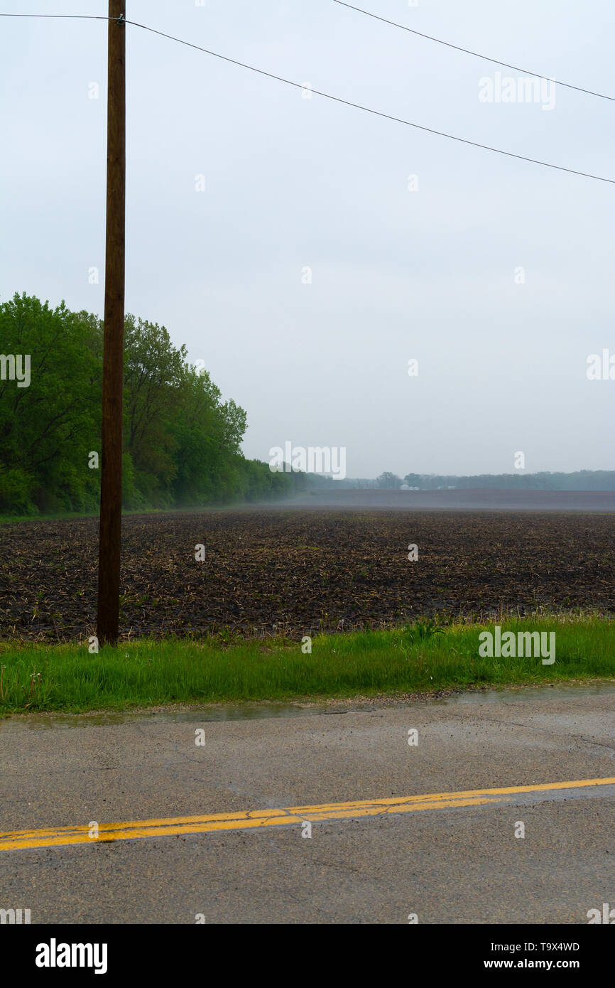Street view of wet country road and farmland as the rain falls in rural ...