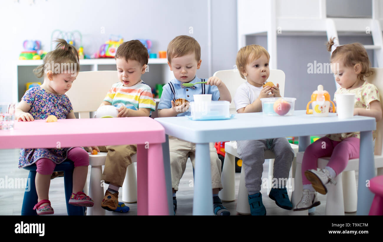 Nursery babies eating food. Kids have lunch in day care or kindergarten ...