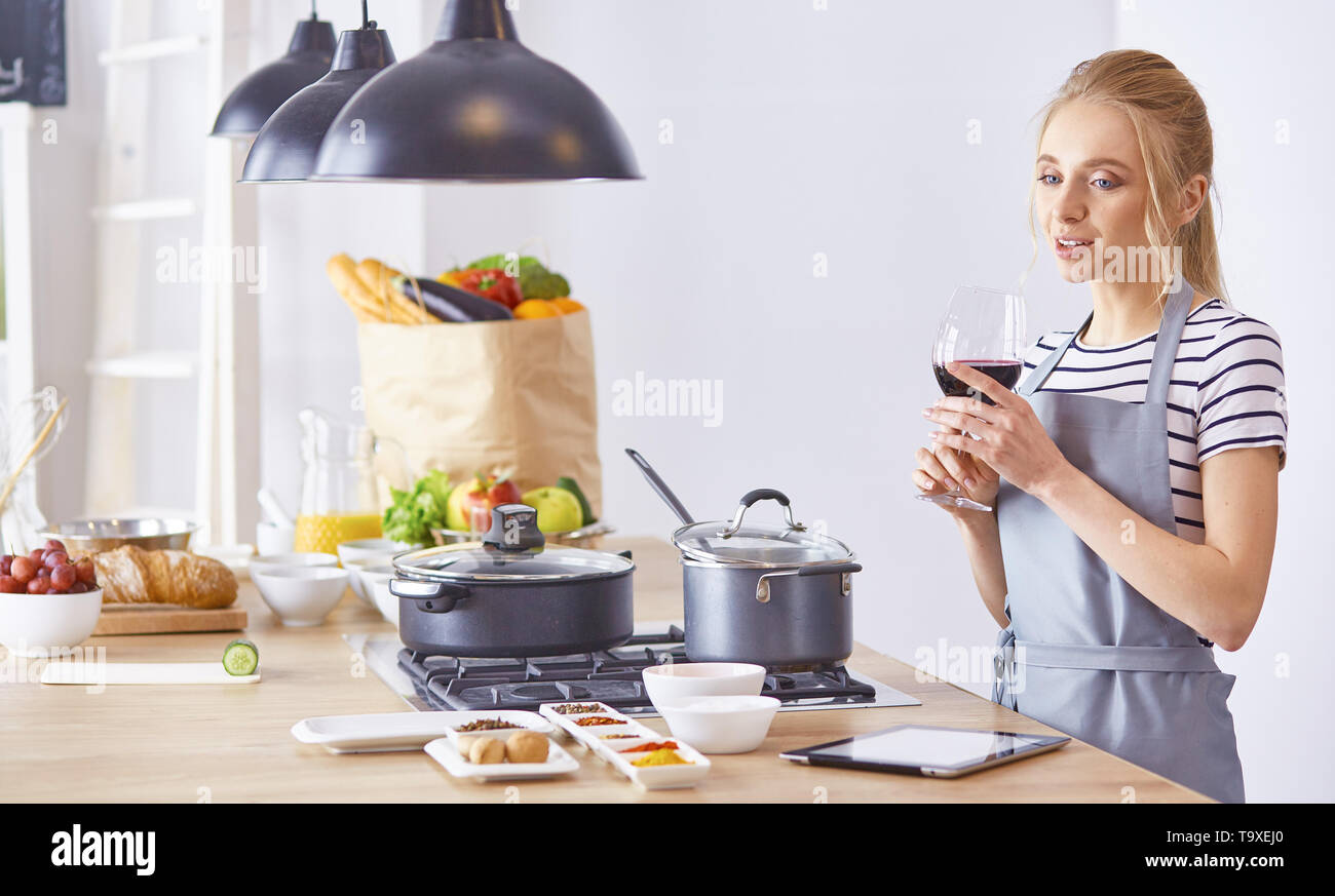 Beautiful woman in kitchen is drinking red wine Stock Photo - Alamy