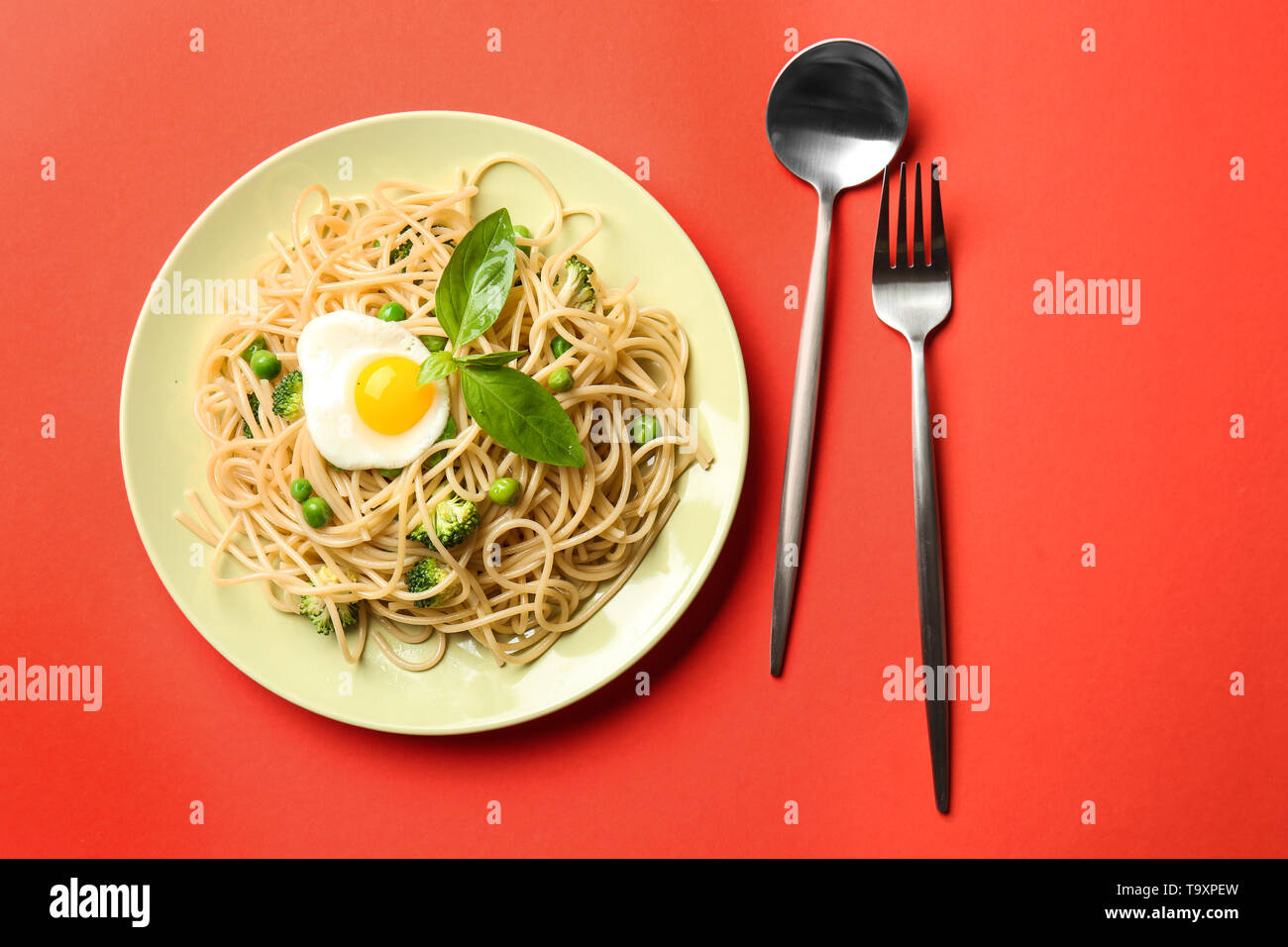Plate with tasty pasta and fried egg on color background Stock Photo ...