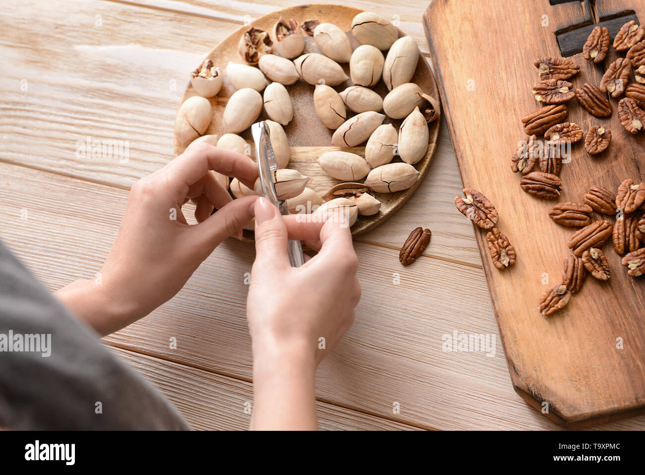 Woman cracking pecan nuts on wooden table Stock Photo - Alamy