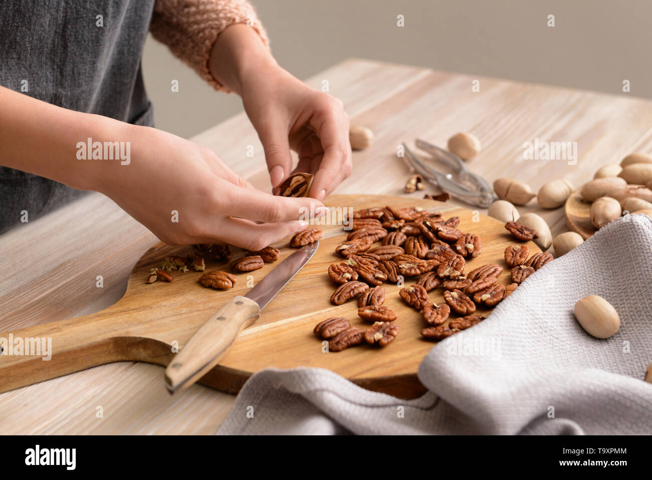 Woman cracking pecan nuts at wooden table, closeup Stock Photo - Alamy