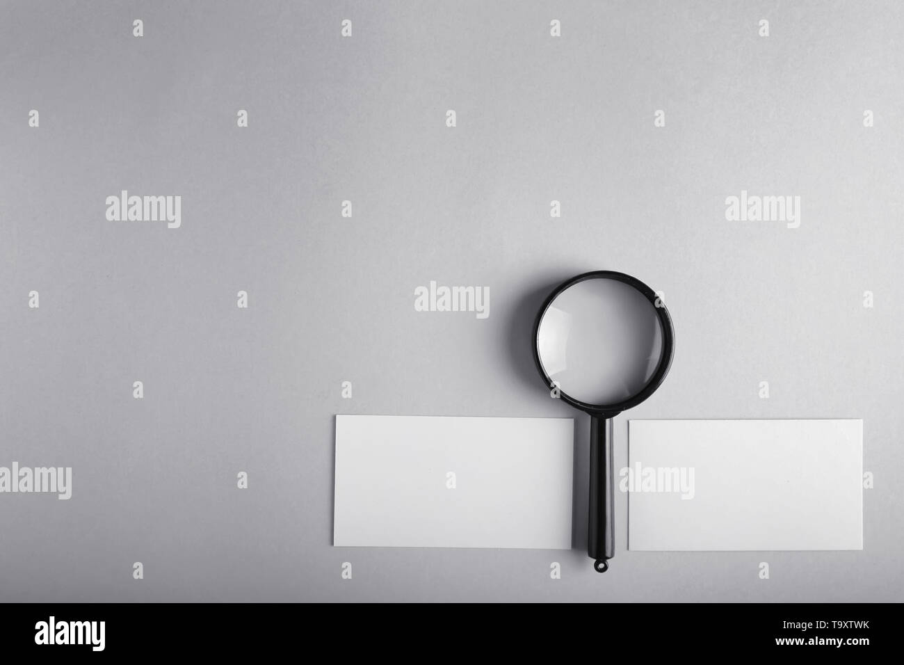 Blank business cards and magnifying glass on grey background Stock ...