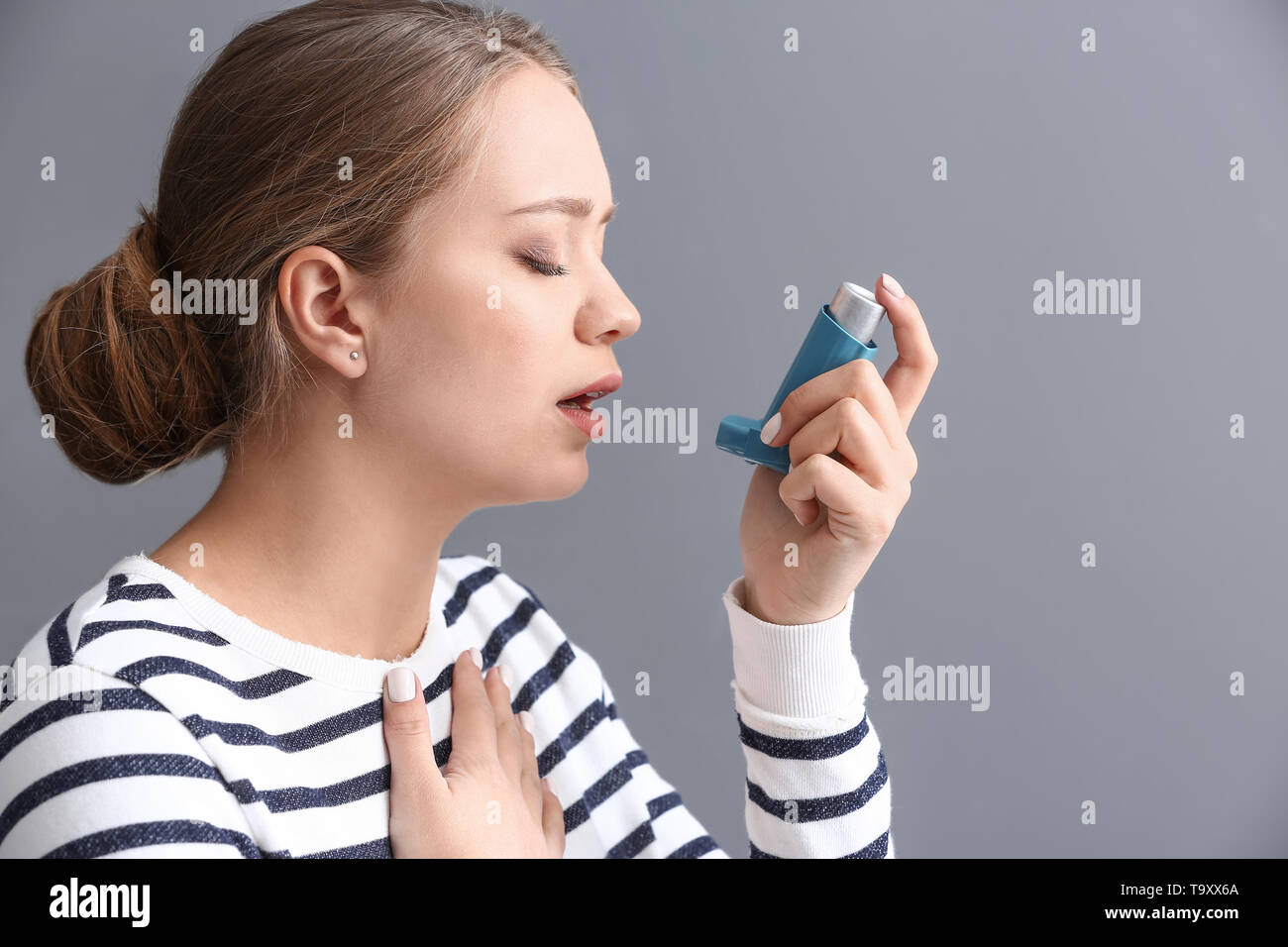 Young woman with inhaler having asthma attack on grey background Stock ...