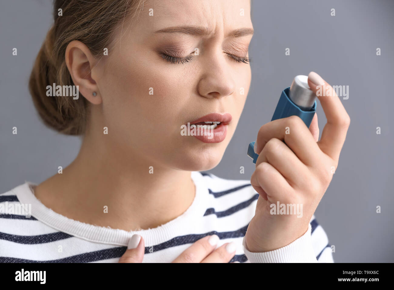 Young woman with inhaler having asthma attack on grey background Stock ...