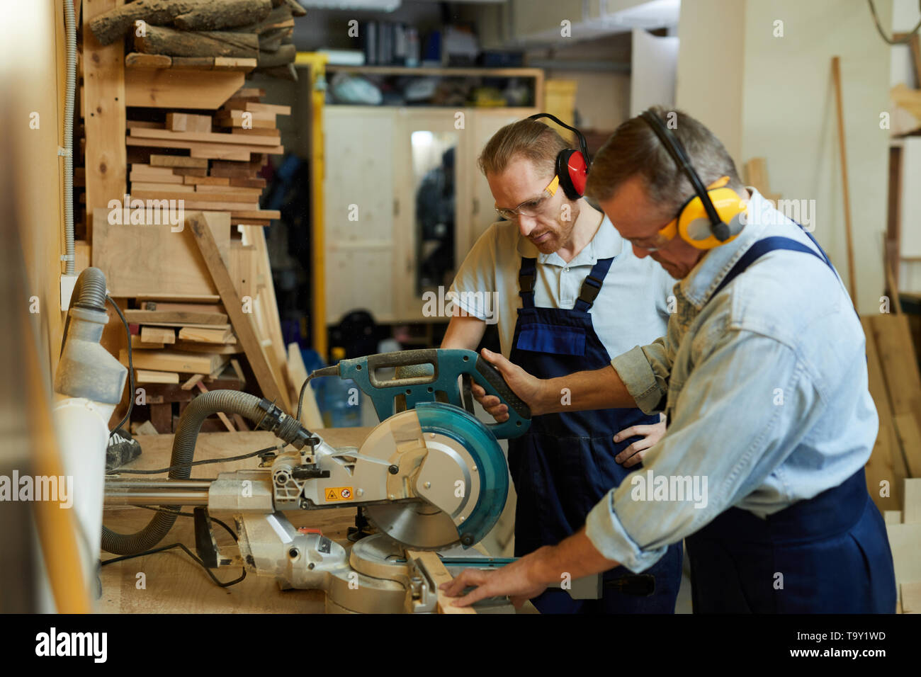 Side view portrait of carpenter cutting wood using disksaw while ...
