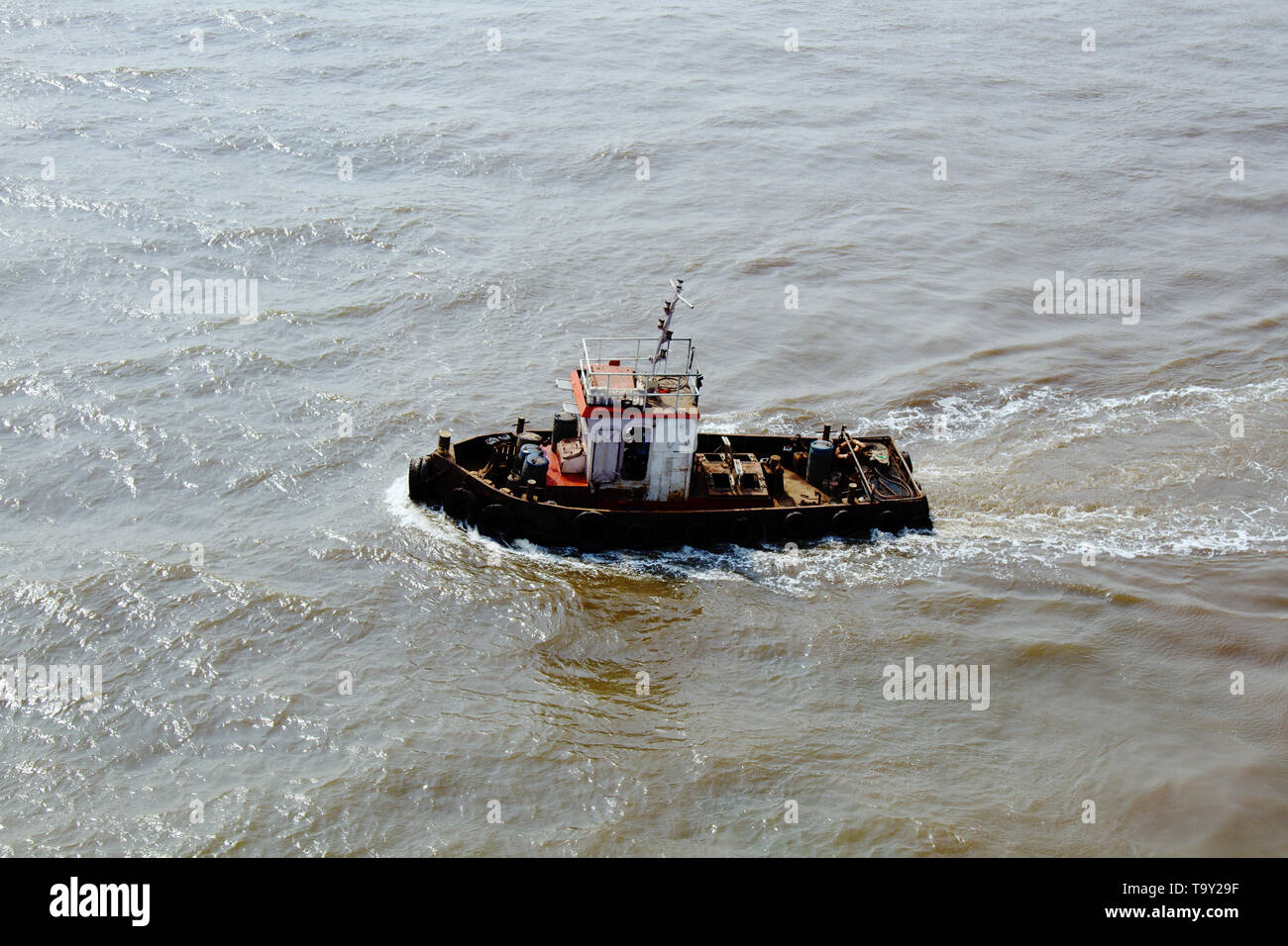small tug boat swings in the waves of the Arabian sea like a sliver ...