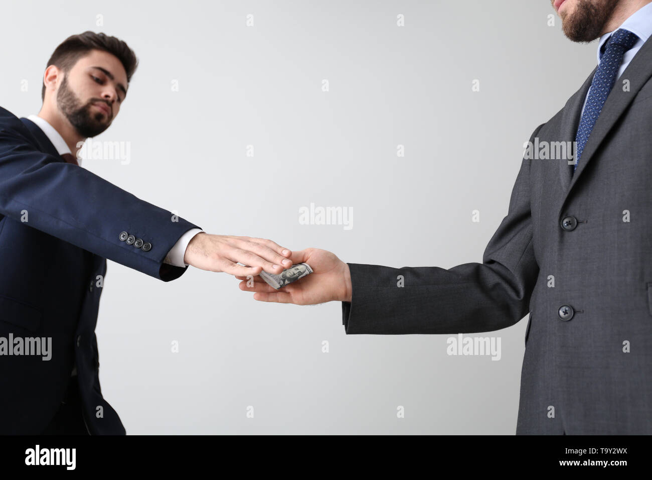 Businessman taking bribe from man on light background. Concept of ...
