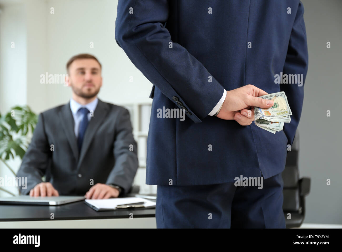 Man hiding bribe for businessman behind back in office. Concept of ...