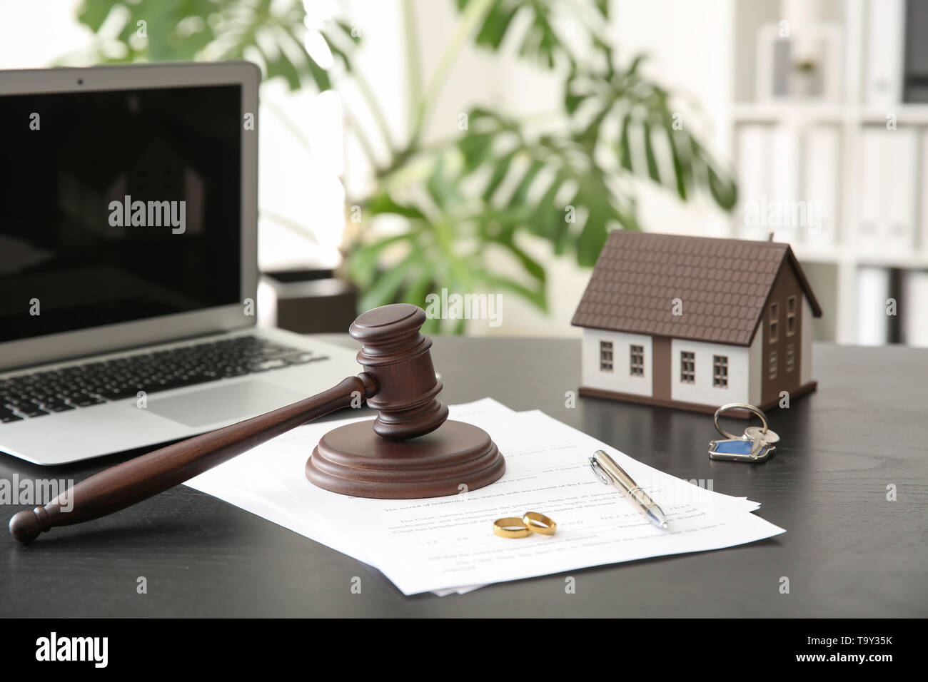 Rings with decree of divorce, judge gavel and house model on table ...