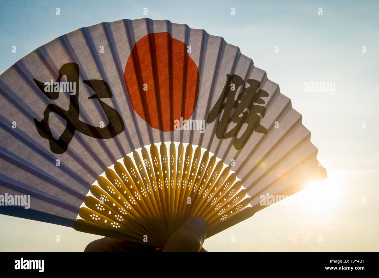 Hand of sports supporter holding a fan decorated with kanji characters ...