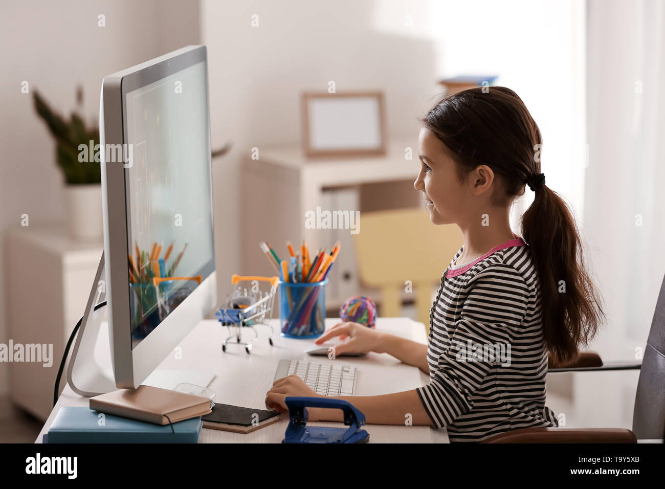 Cute little girl playing computer game at home Stock Photo - Alamy