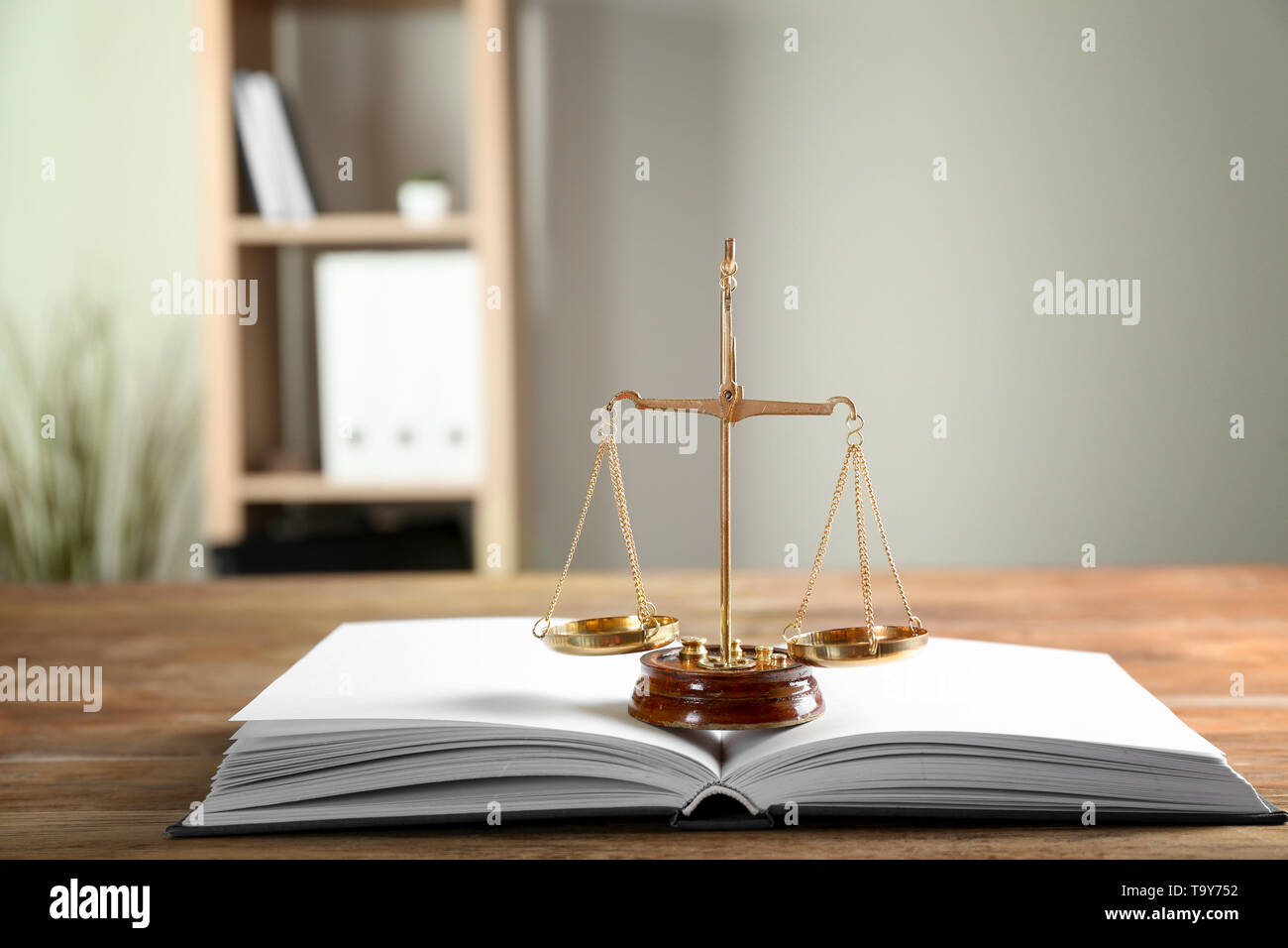 Scales of justice and open book on wooden table Stock Photo - Alamy